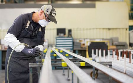 A worker completes metal finishing on stringers for aircraft wings ...